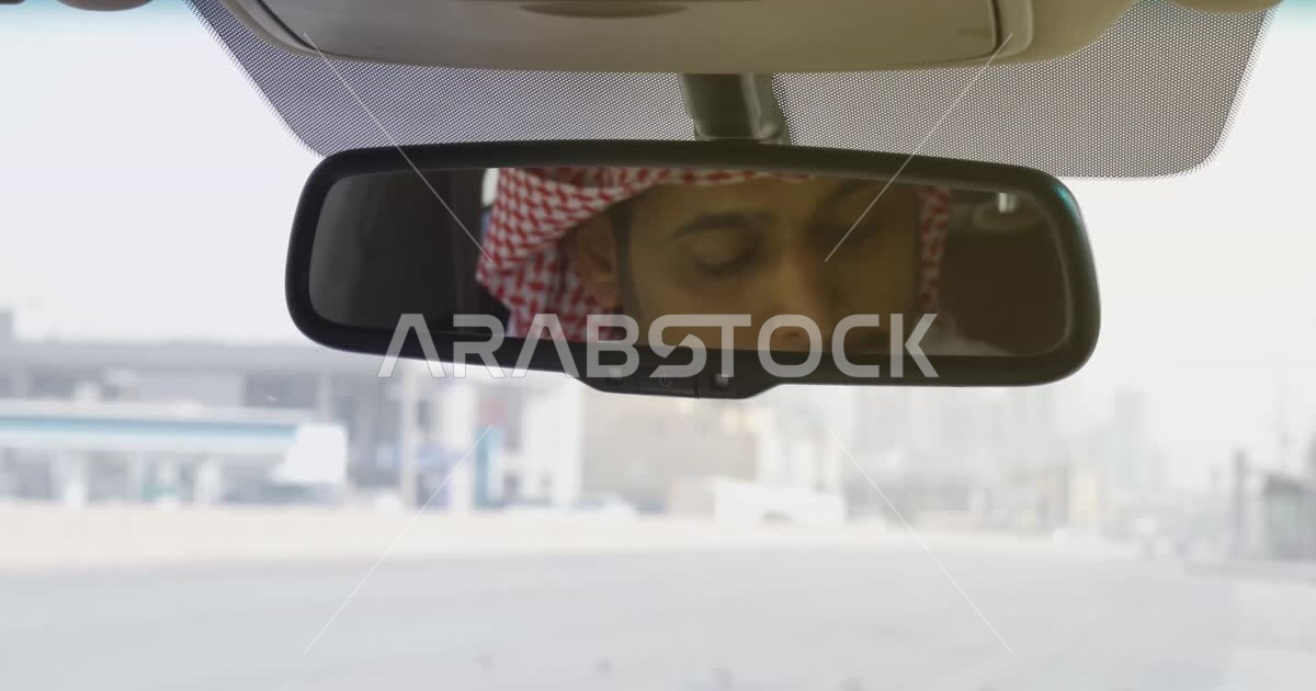 Reflection on the mirror of a Saudi Arabian Gulf driver driving a taxi ...