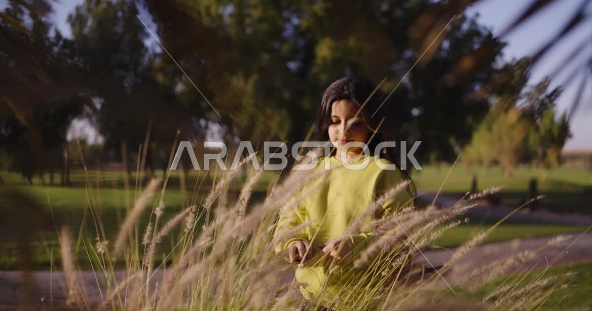 A Saudi Gulf Arab girl in a recreational park, wheat fields and farms ...
