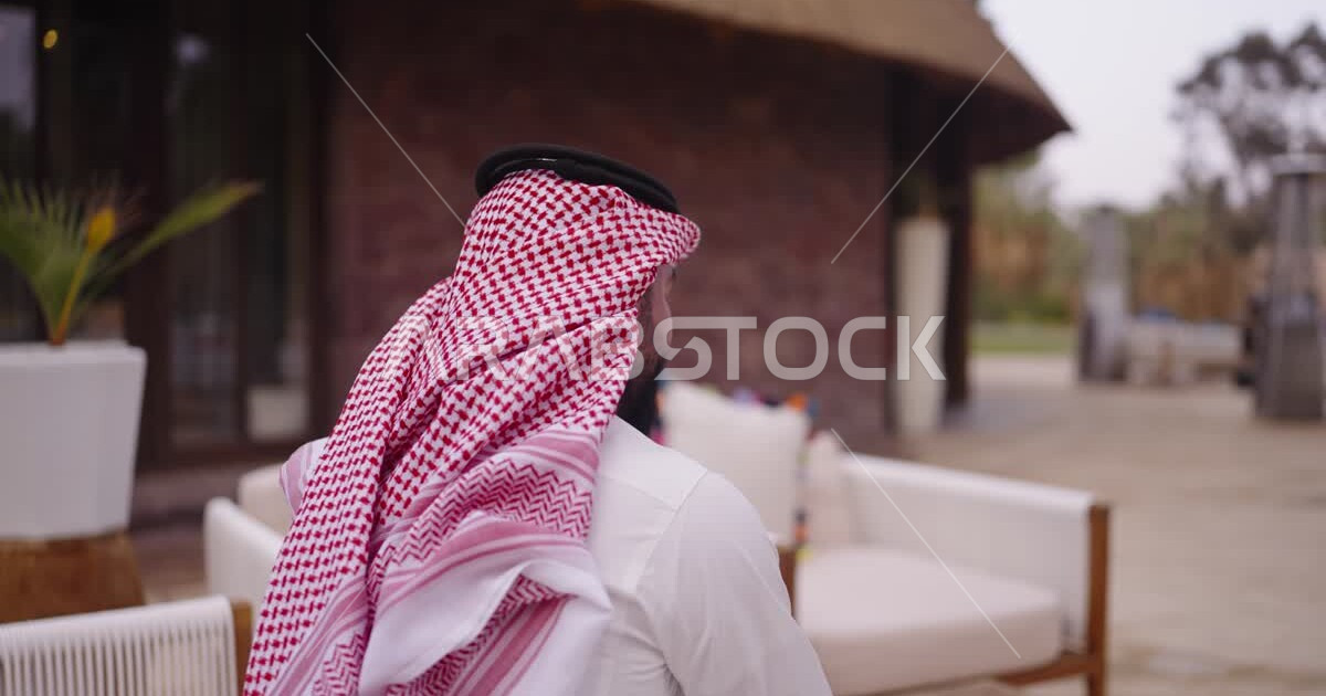 An angle from the back of a Saudi Arabian Gulf man, dressed in ...