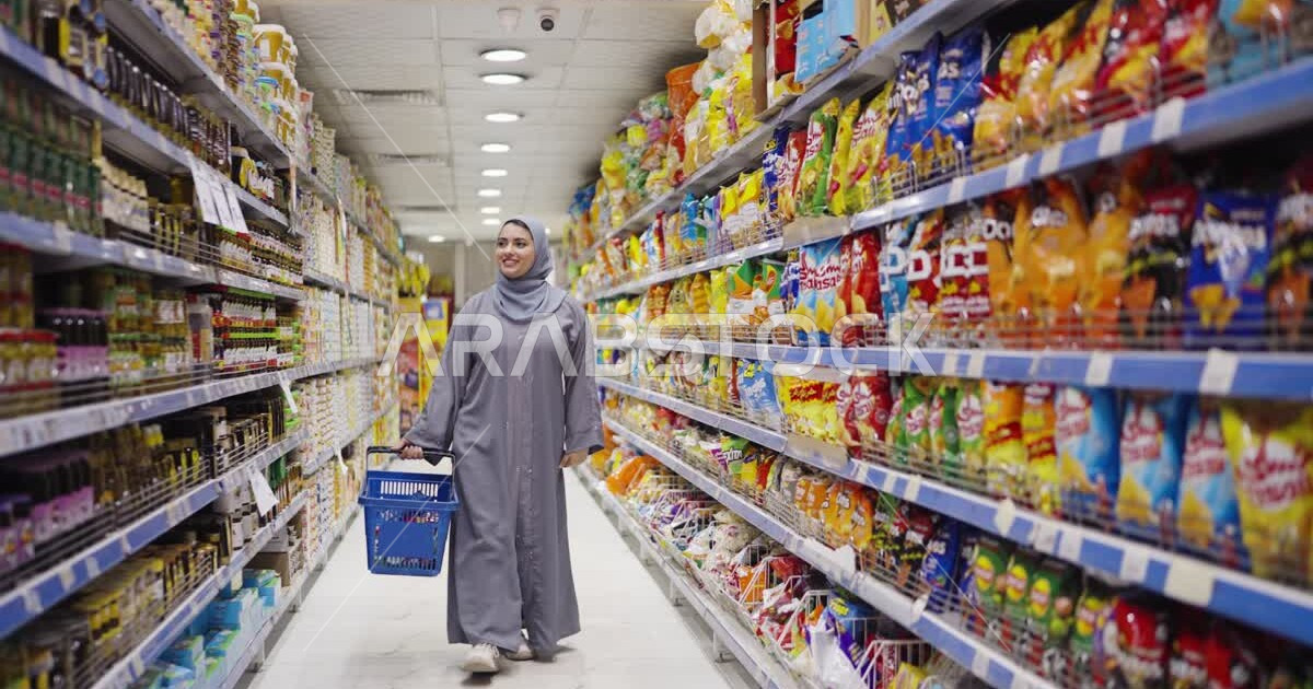 A Saudi Arabian Gulf woman in the supermarket, shopping basket, brands ...