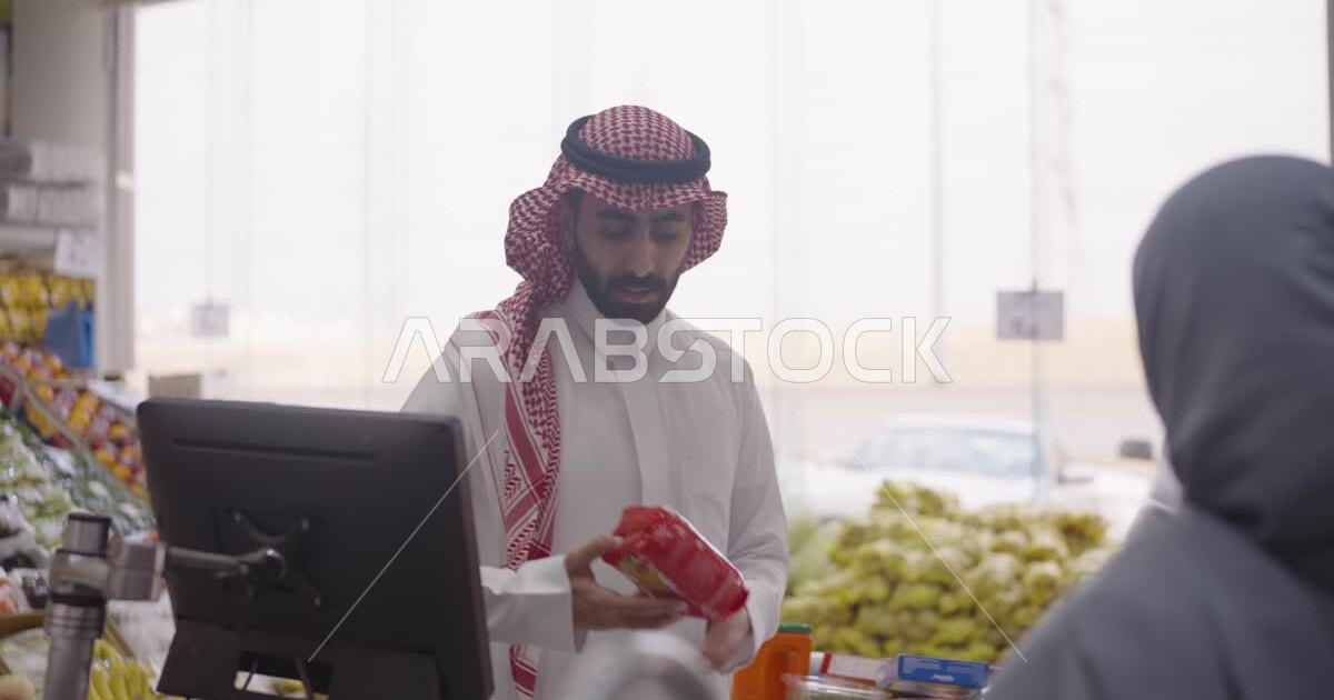 A Saudi Arab Gulf woman in the supermarket, verifying the value of ...