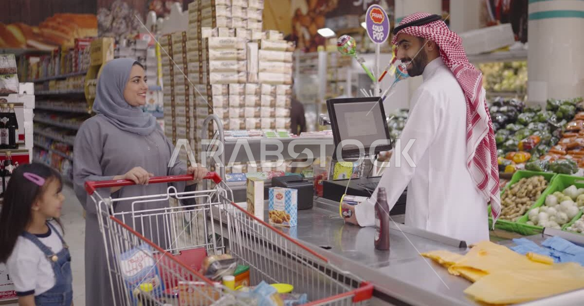 A Saudi Arabian Gulf woman with her daughter in the supermarket, having ...