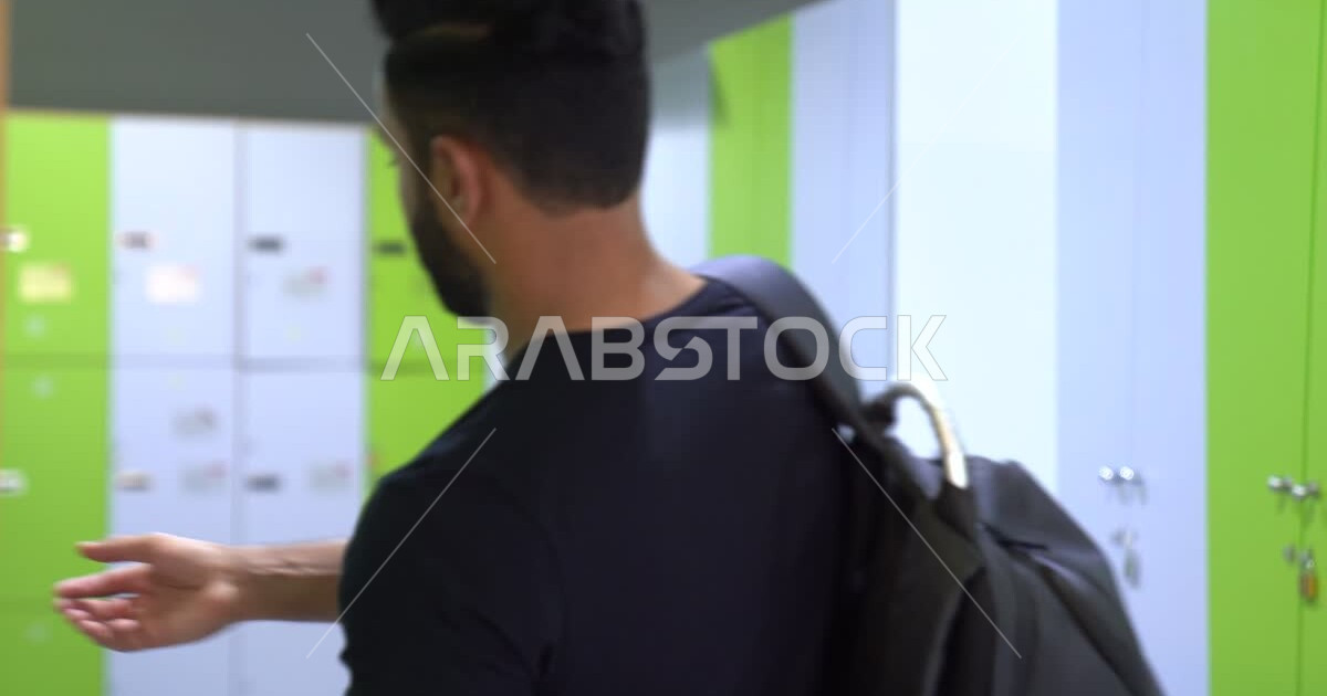 A young Saudi man opens the locker in the gym and prepares for training ...