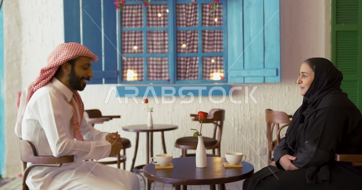 A Saudi Arabian Gulf couple sitting in a café, ordering coffee from the ...