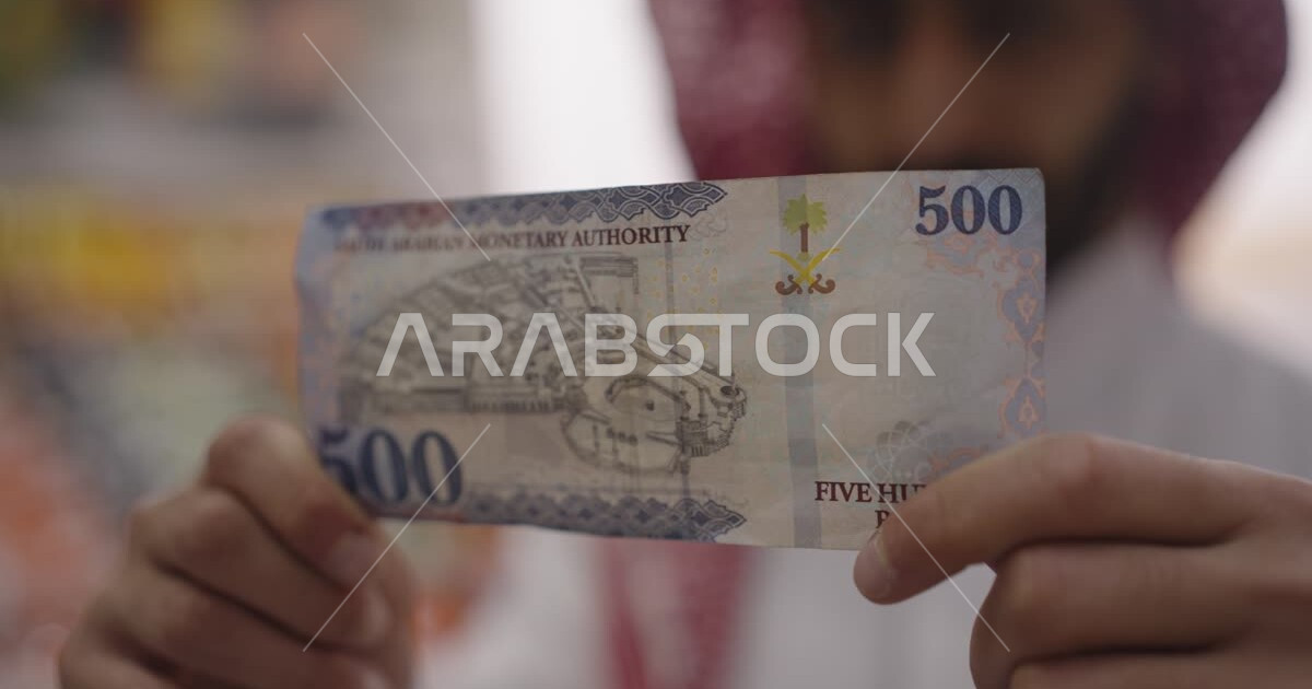 A Saudi Gulf Arab accountant carries banknotes (500 riyals) in the ...