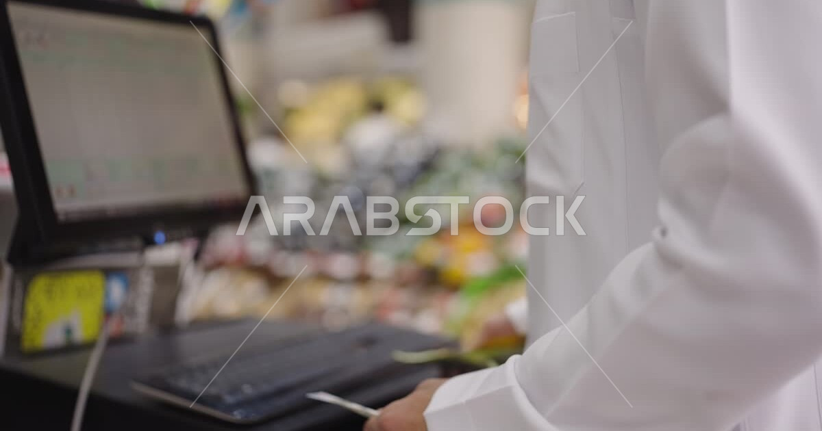 A Saudi Arabian Gulf accountant working on a computer, cash payment ...