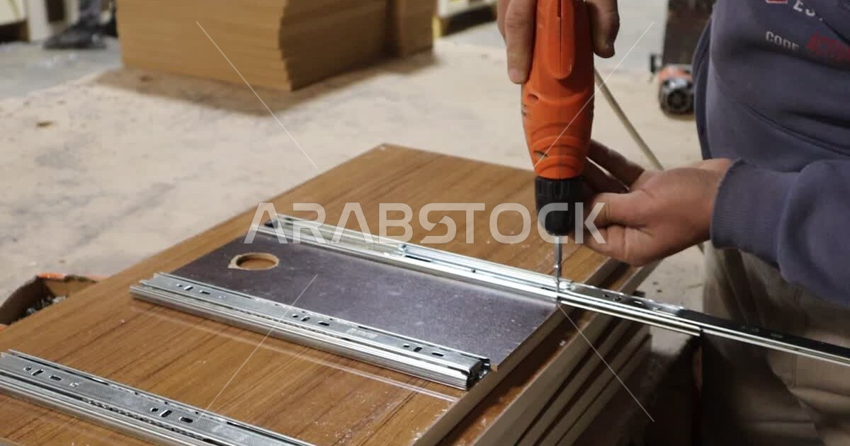 Close-up of desk drawer tractor installation, electric drill use ...