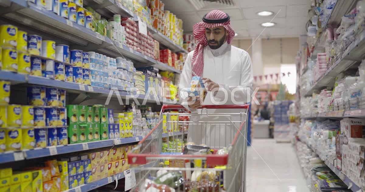 A Saudi Arabian Gulf man shopping in the supermarket, reading the ...